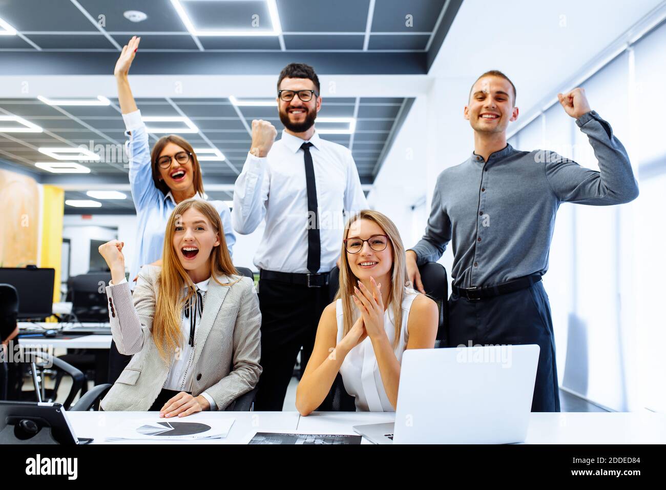 Successful business team standing together celebrating victory showing ...