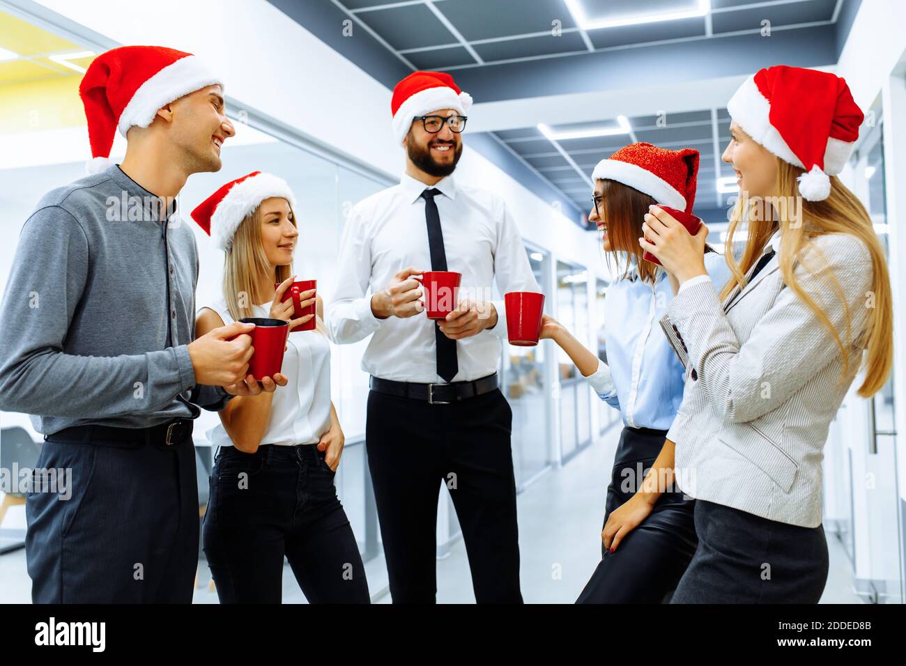 working team in Santa Claus hats, during a break in the office, greets ...