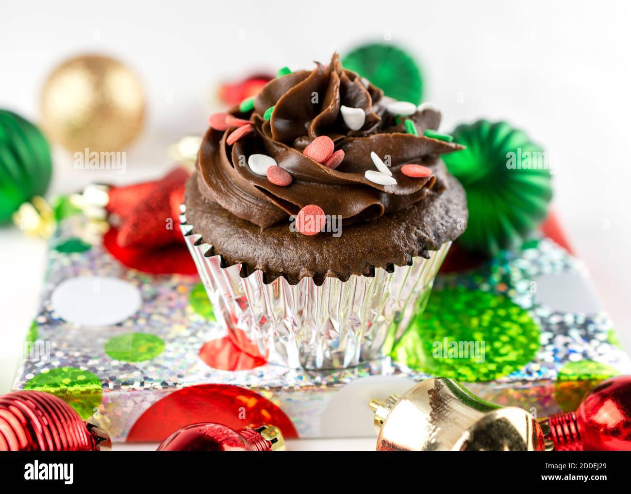 A Christmas Chocolate Cupcake sits on a wrapped foil gift with ...
