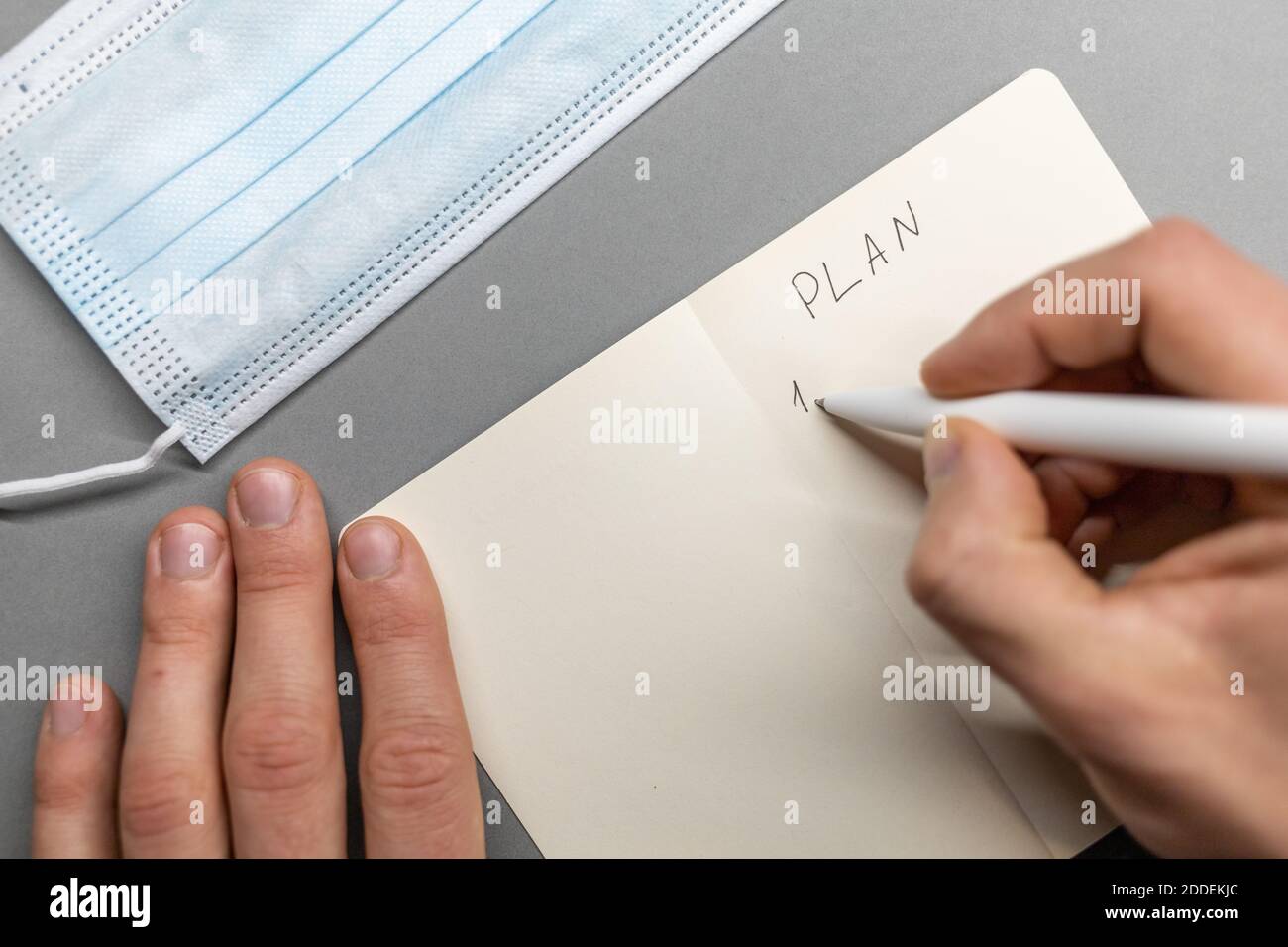 open notebook and face mask hand writing plan Stock Photo - Alamy