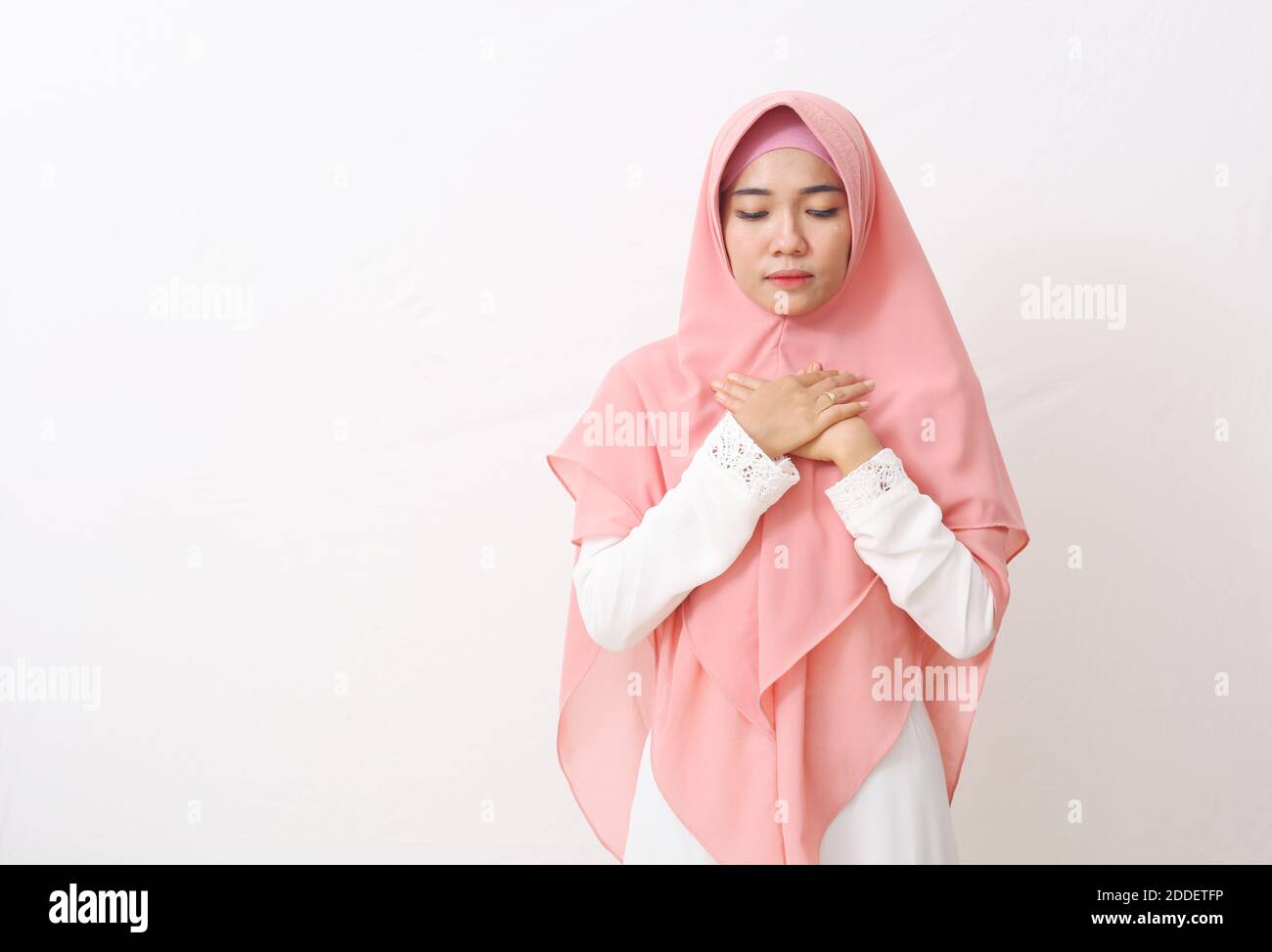 Faithful asian muslim woman closes eyes and keeps hands on chest near ...