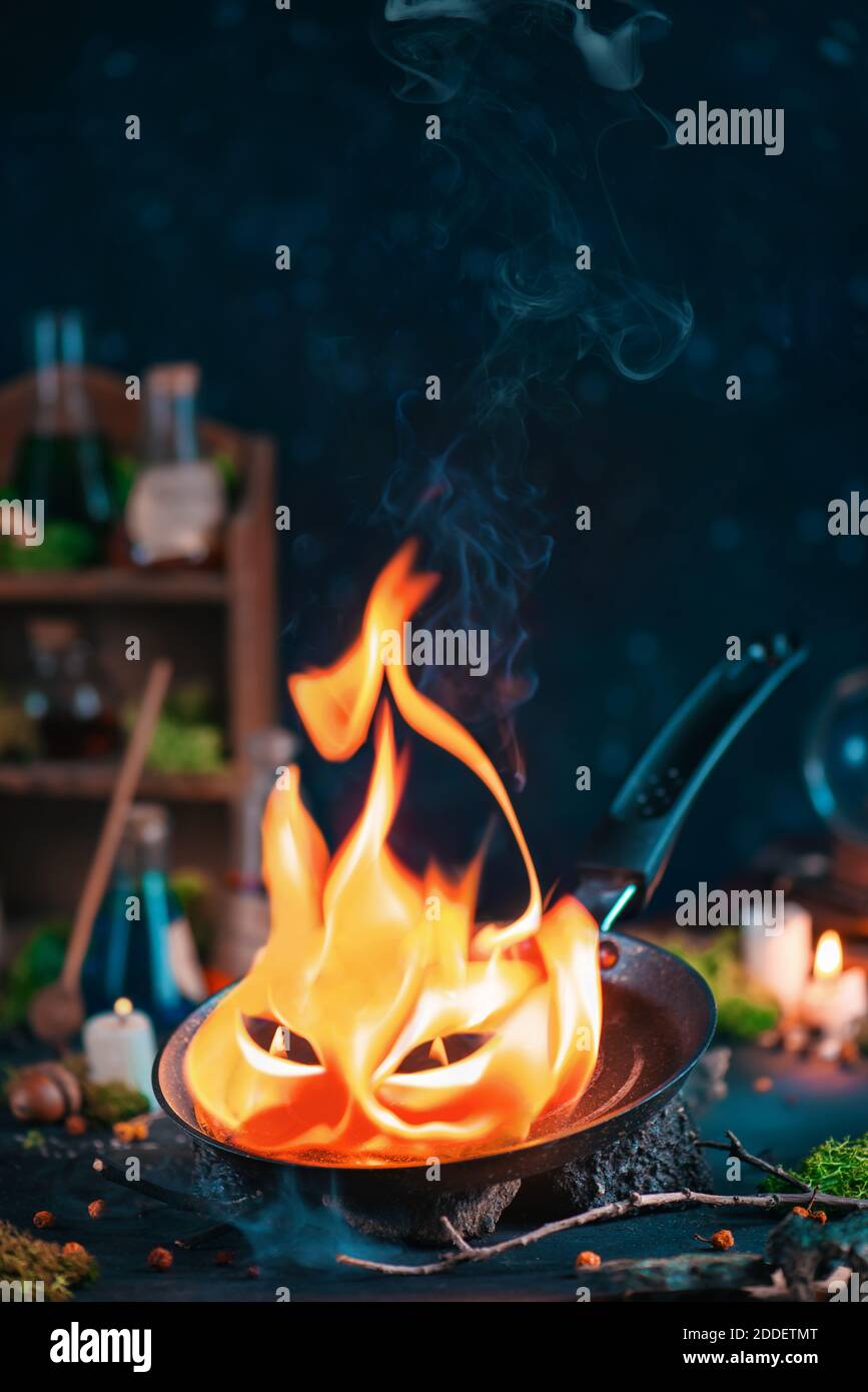 Grumpy fire spirit on a pan, summon spell, magical still life with copy ...