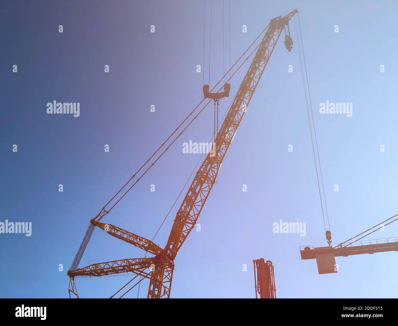 Tower cranes and blue sky with sun flare. Lifting machinery at ...
