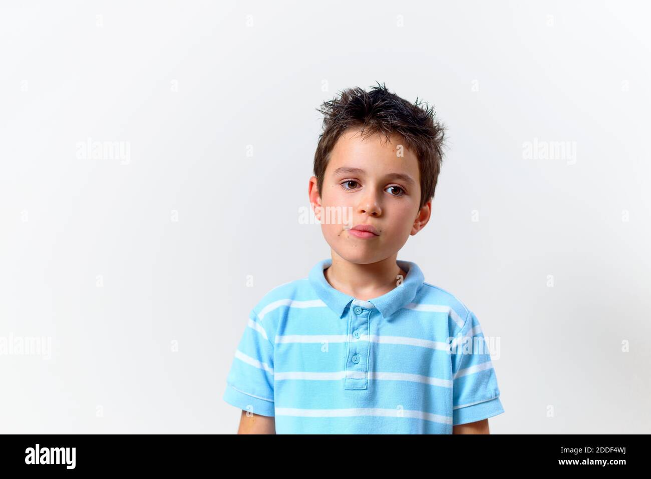 The boy in a blue T-shirt with a brooding face looks somewhere from the ...