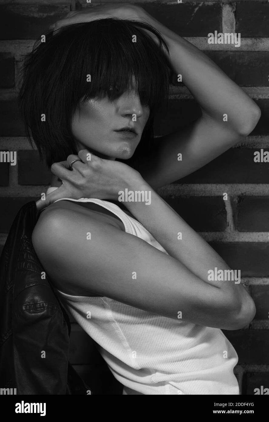 Androgyny female model in Heroin chic style near brick wall. Old style ...