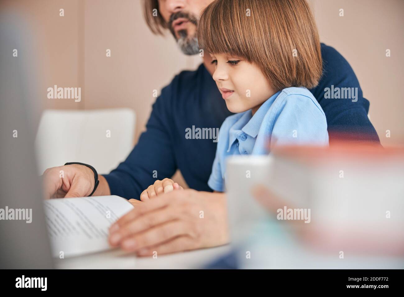 Calm boy and his parent doing school homework together Stock Photo - Alamy