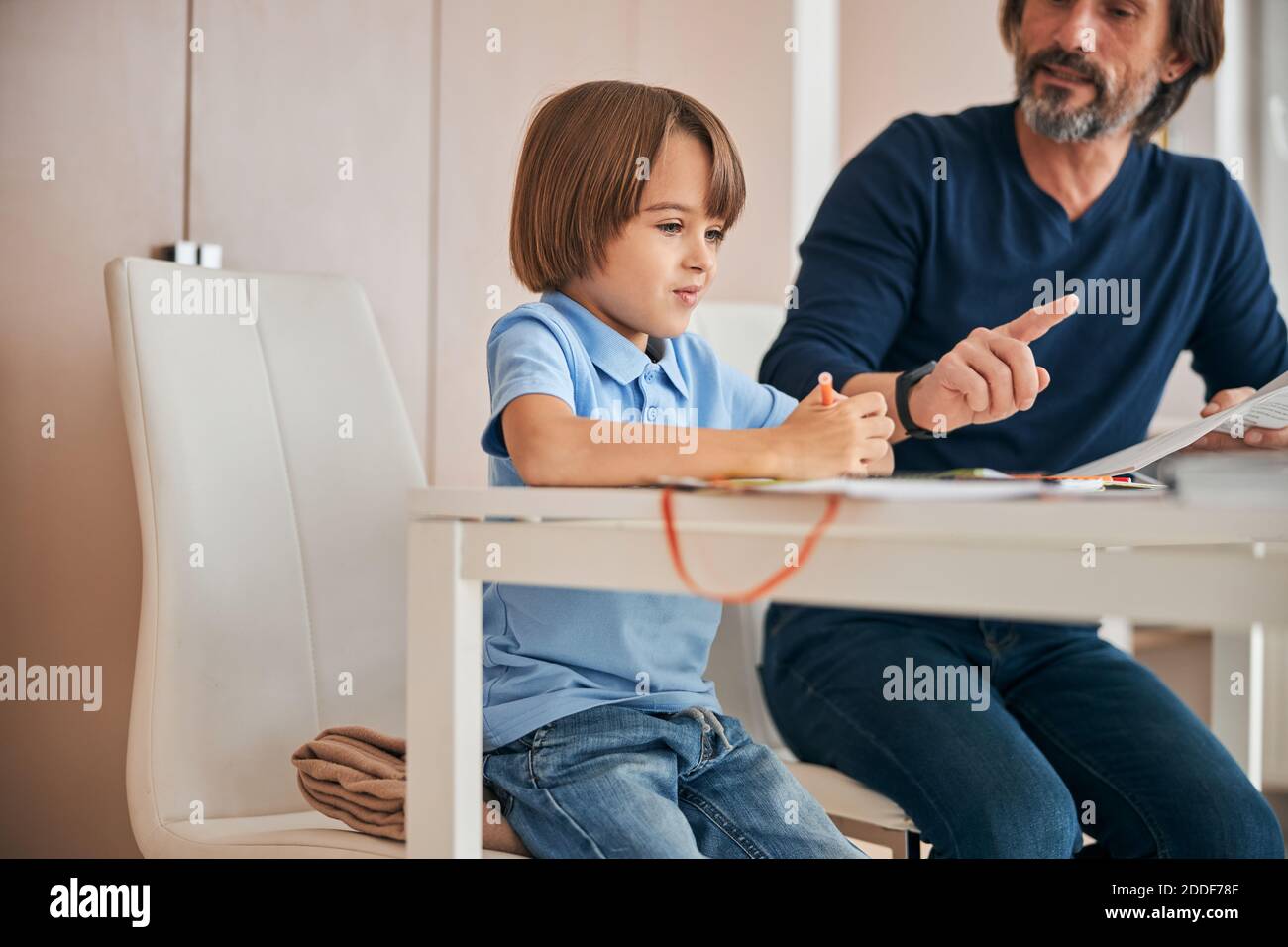 Clever kid doings tasks and parent helping him Stock Photo - Alamy