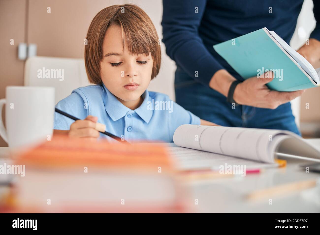 Child doing homework and his parent checking it Stock Photo - Alamy