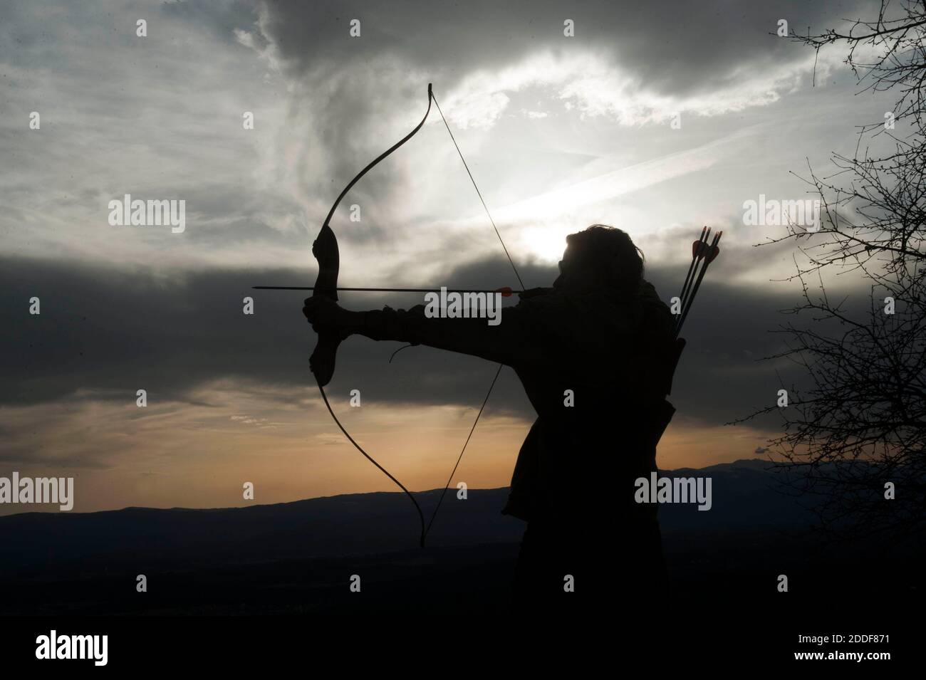 Archer with a bow and arrow aiming in the twilight Stock Photo - Alamy