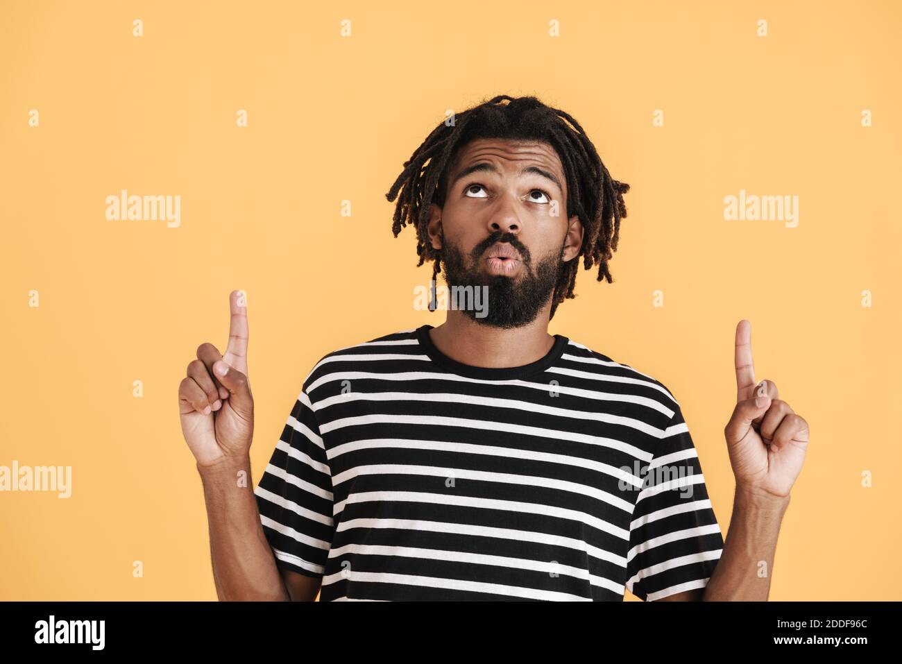 Photo of confused african american guy pointing fingers upward isolated ...