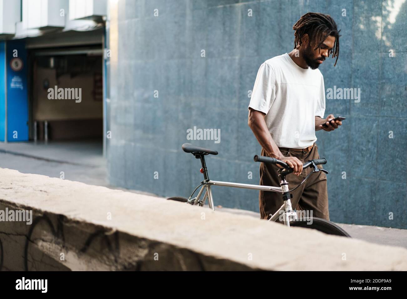 Concentrated african american guy using cellphone while walking with ...