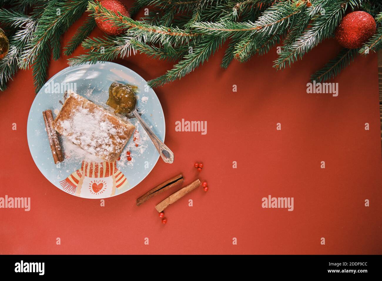 Top view of a strudel on a Christmas plate near cinnamon sticks ...