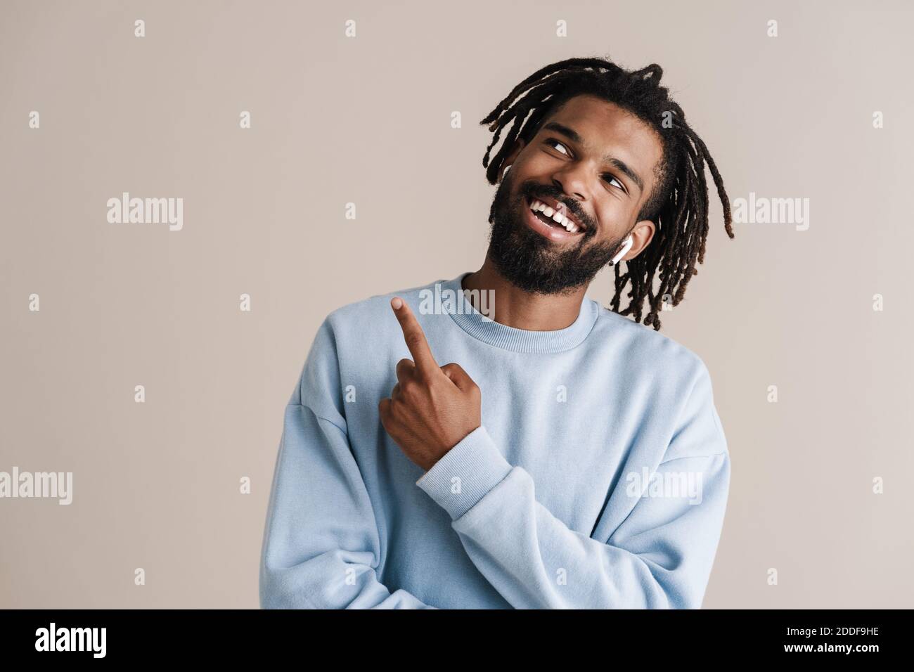 Cheerful african american guy in earphones pointing finger upward ...
