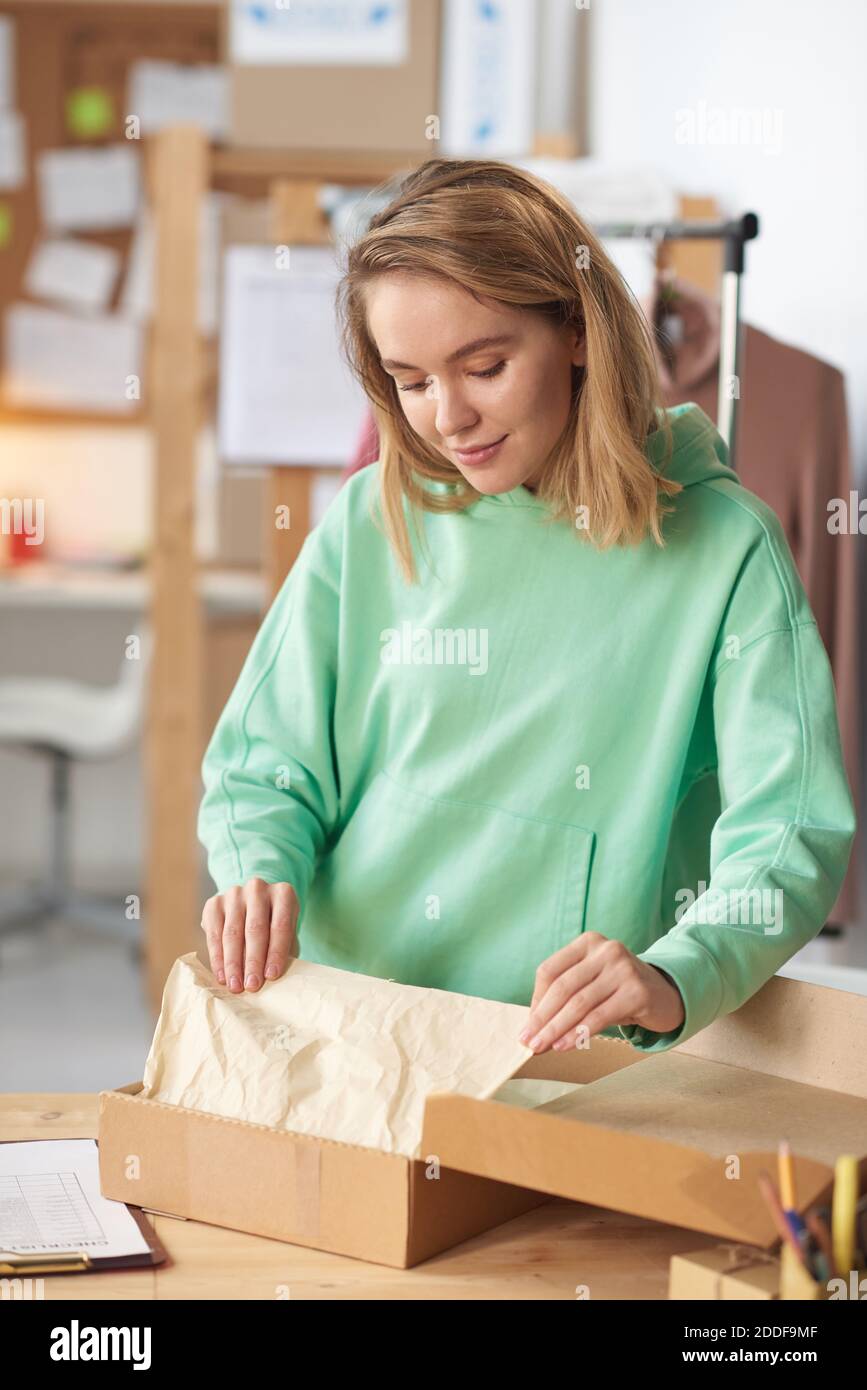 Young woman packing the parcel at the table for delivery to the ...