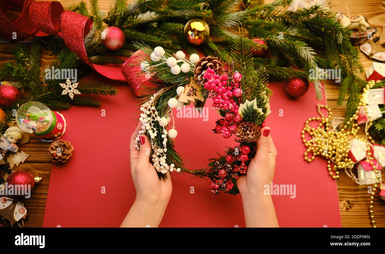 Hands making rustic Christmas wreath s on a red background. Atmospheric ...
