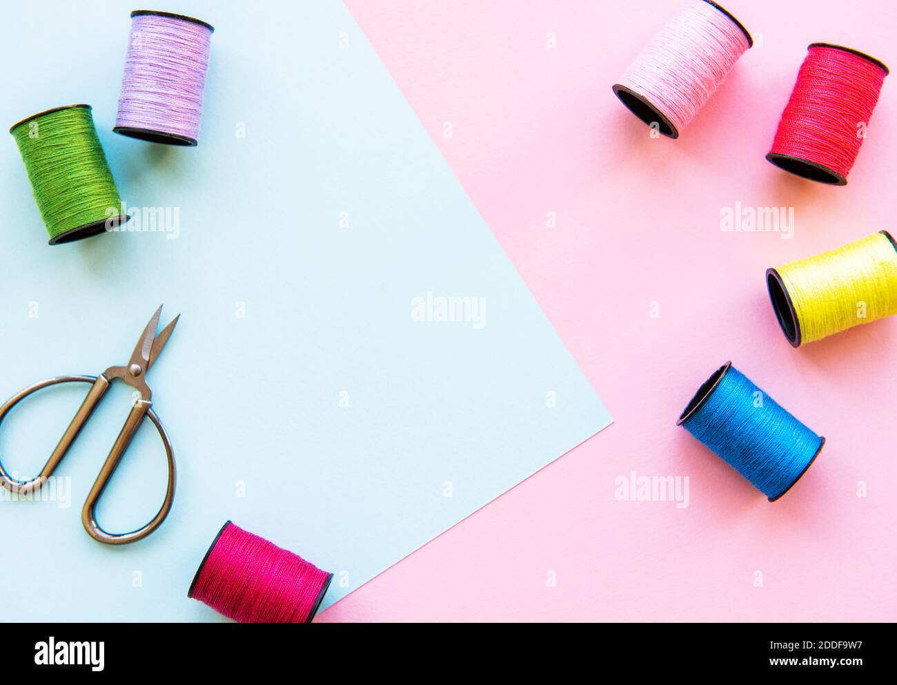 Flat lay of colored thread rolls and Scissors for sewing on two tone ...