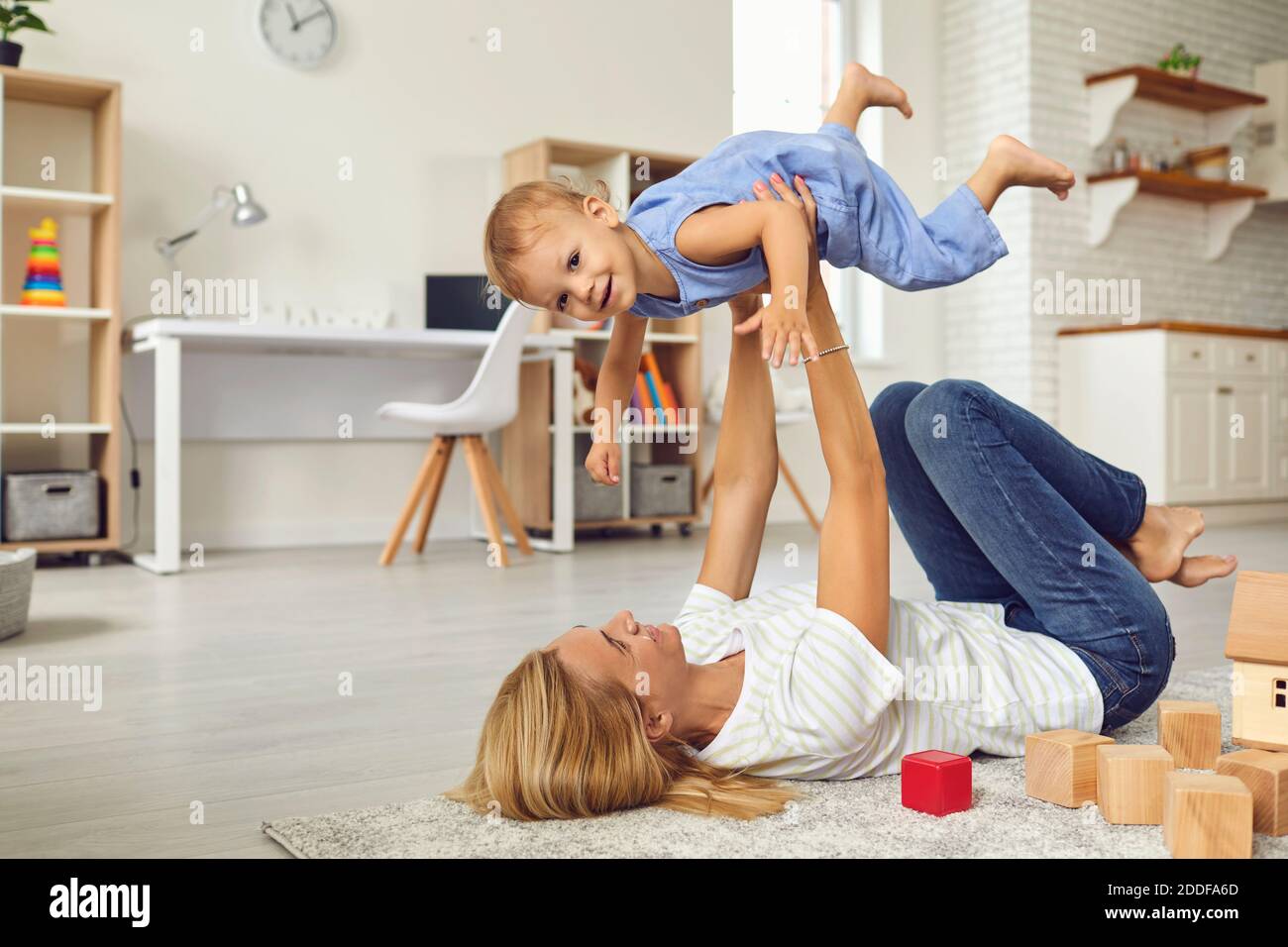 Happy mother lying on floor and holding looking at camera smiling baby ...