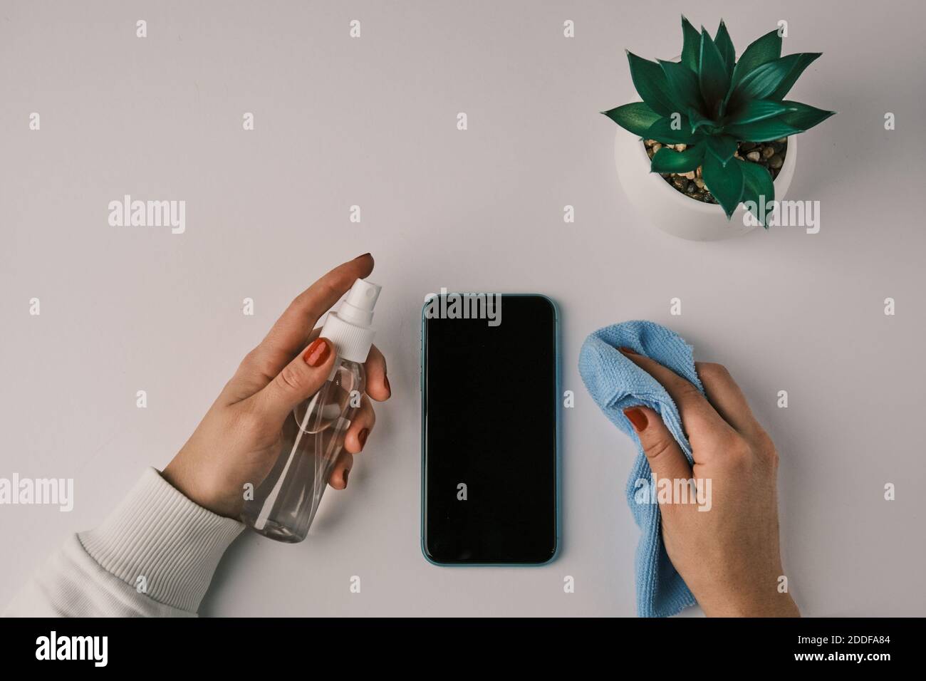 Woman Cleaning And Disinfecting Cell Phone Against Virus on a white ...