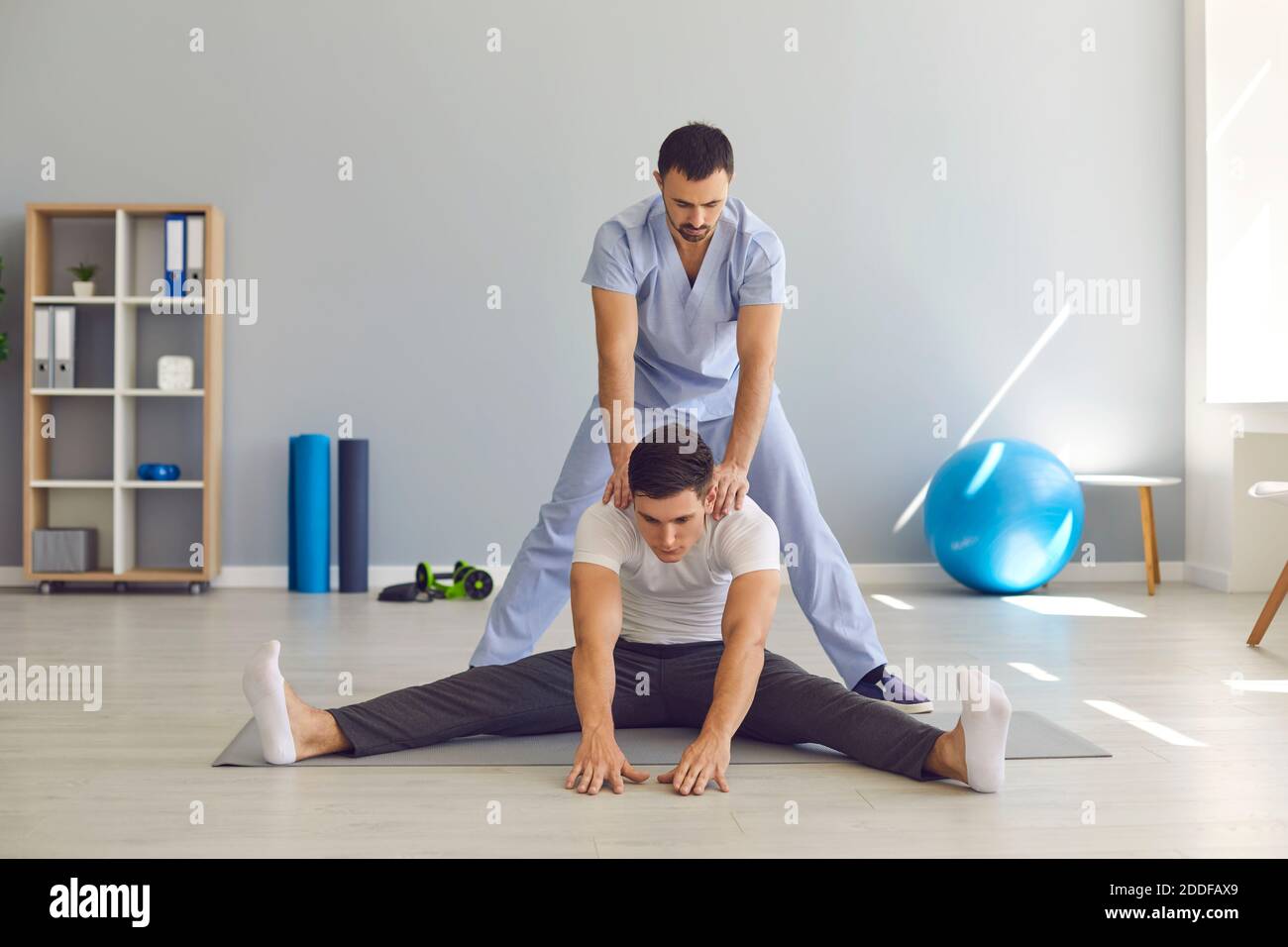 Professional chiropractor pushing and stretching man patients back as ...