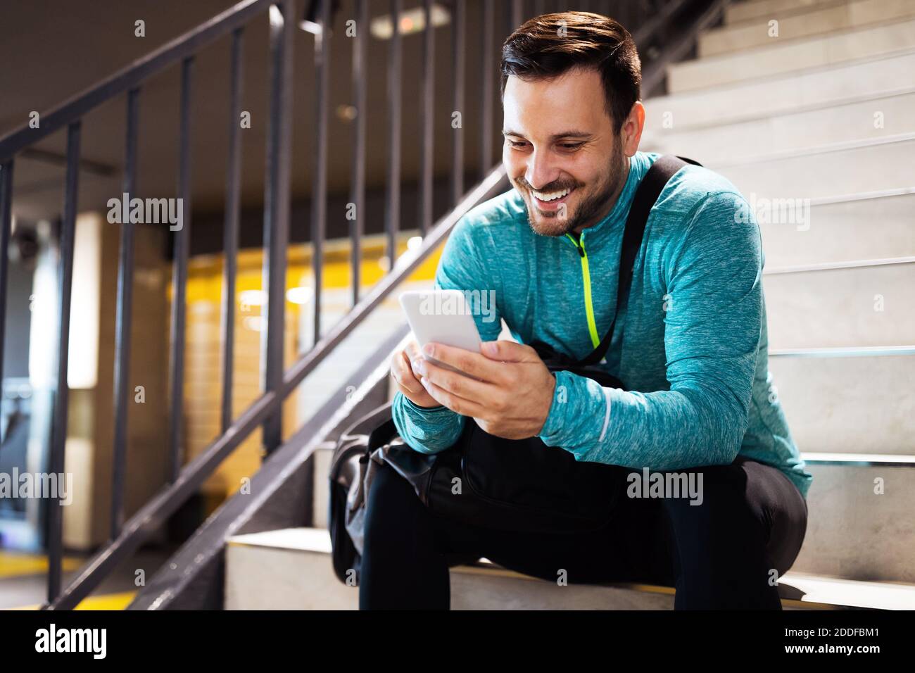 Happy fit man relaxing in the gym after strength exercises for ...