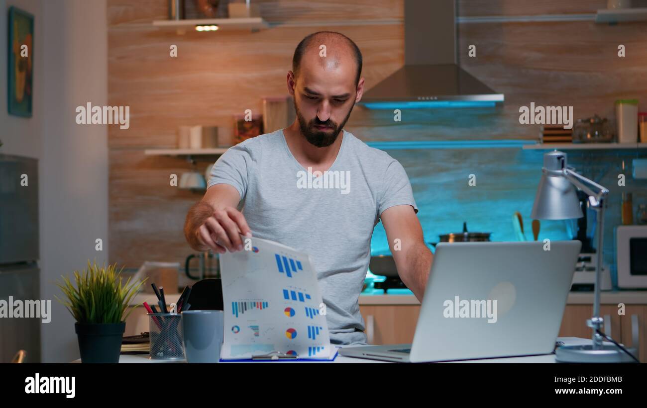 Focused busy entrepreneur checking graphics from clipboard using laptop ...