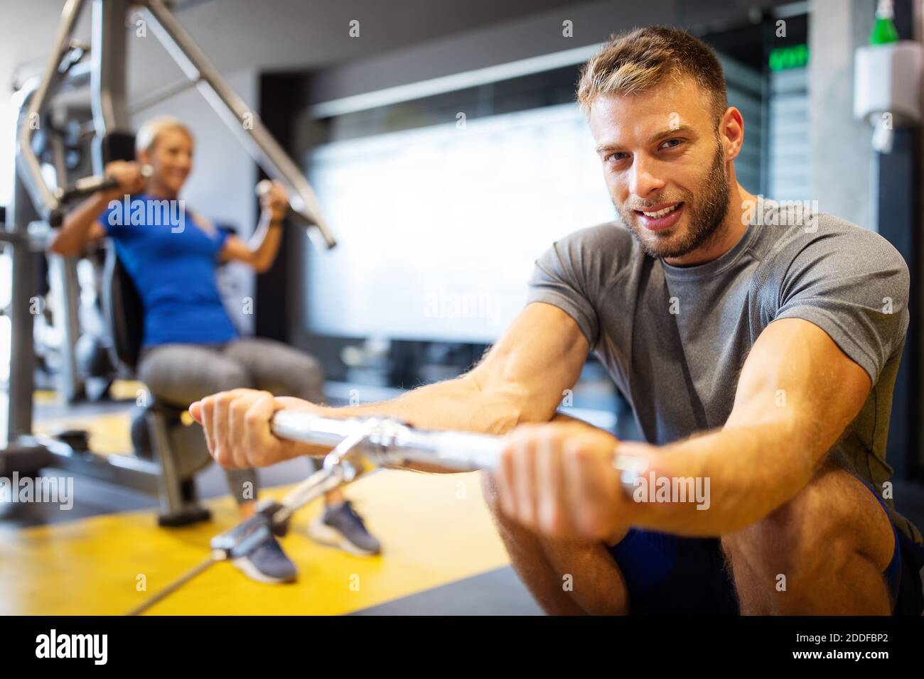 Fit happy man exercising at the gym on a machine Stock Photo - Alamy