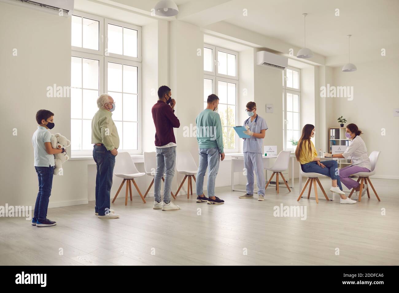 Diverse people standing in line at the hospital and waiting for their ...