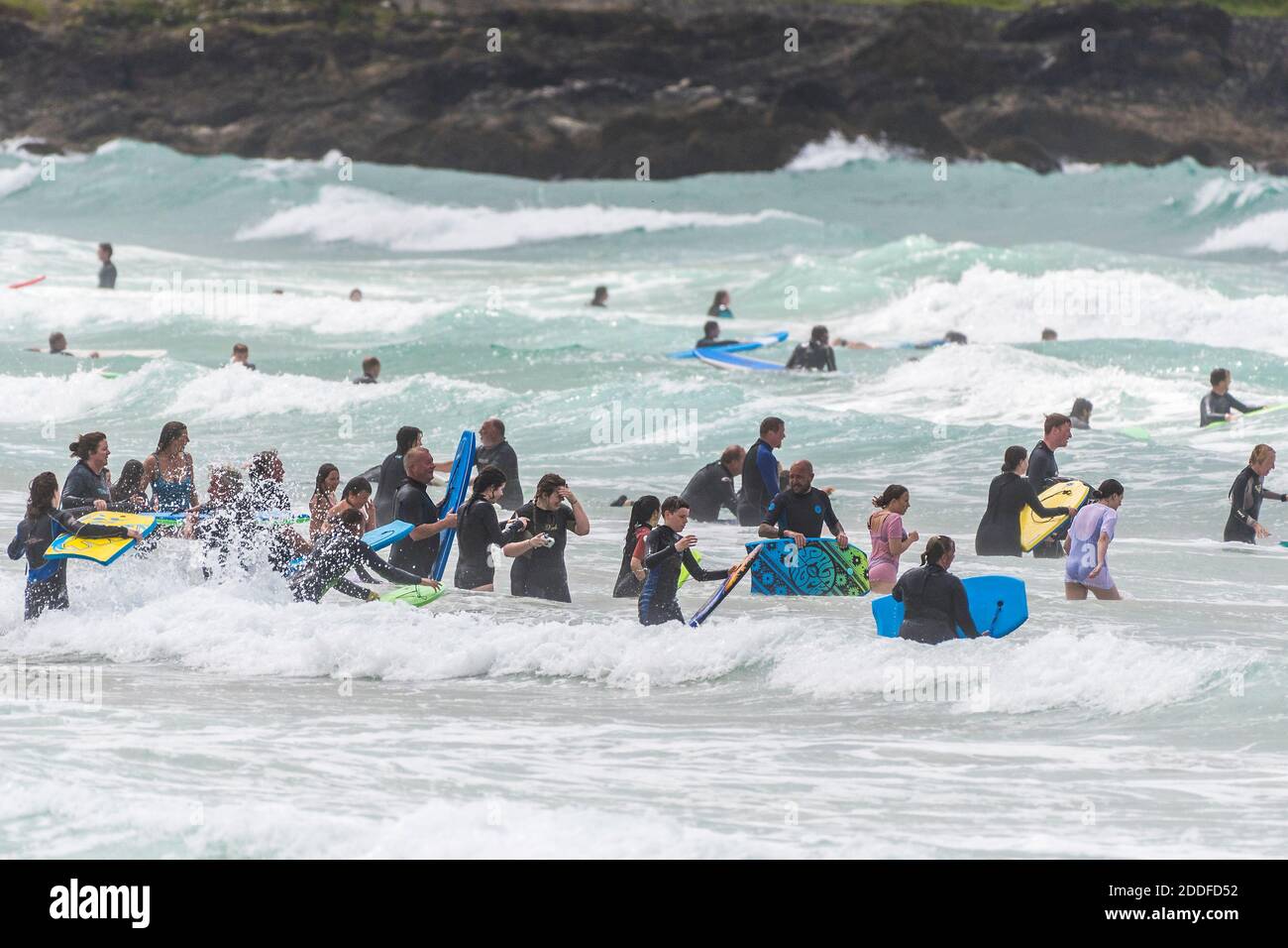 Body boarders in the sea at a busy Fistral Beach in Newquay in Cornwall ...