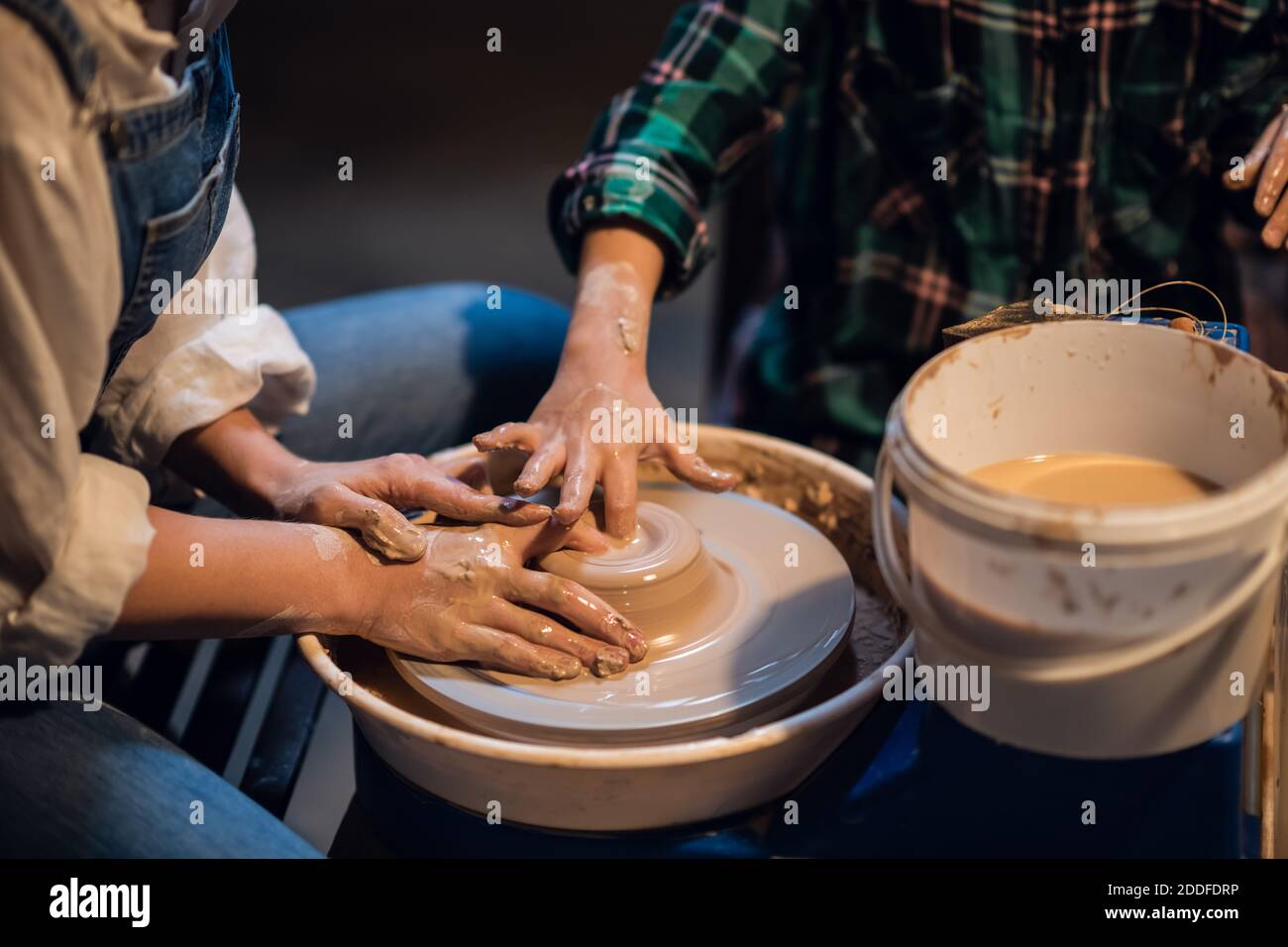 a beautiful woman teacher in her workshop conducts a lesson in clay ...