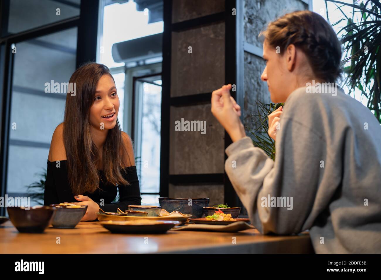Two young girls chatting in an asian style cafe Stock Photo - Alamy