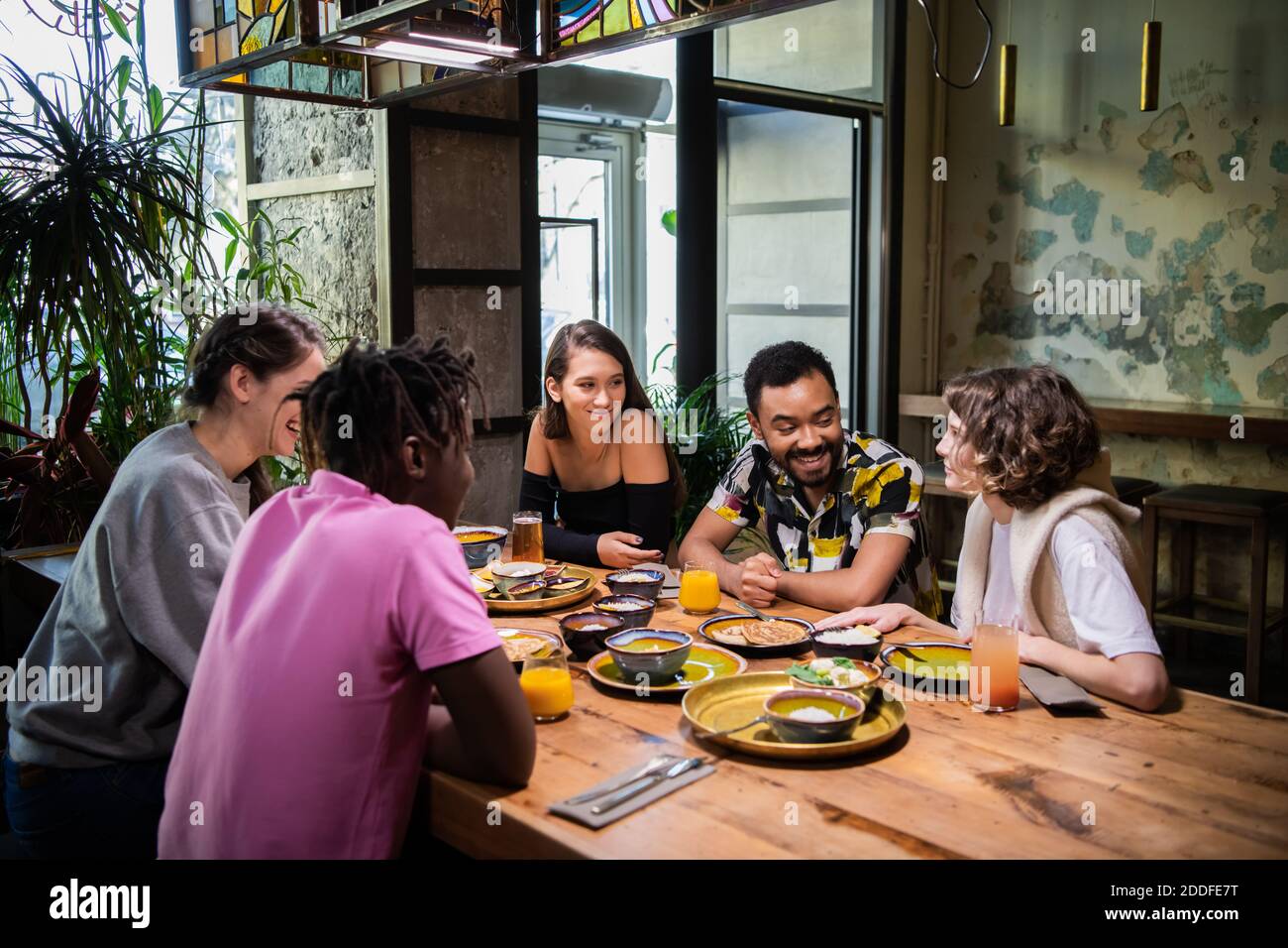 Group of friends sitting and having a meal in a cafe Stock Photo - Alamy