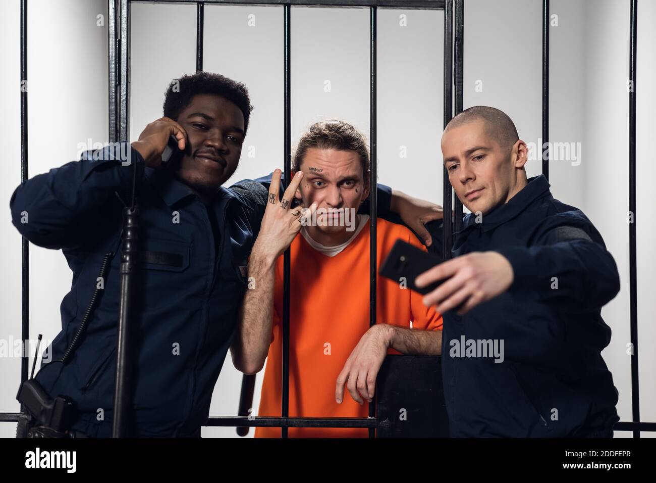 A prisoner with tattoos on his face takes a selfie with his fellow prison guards on a smartphone ...