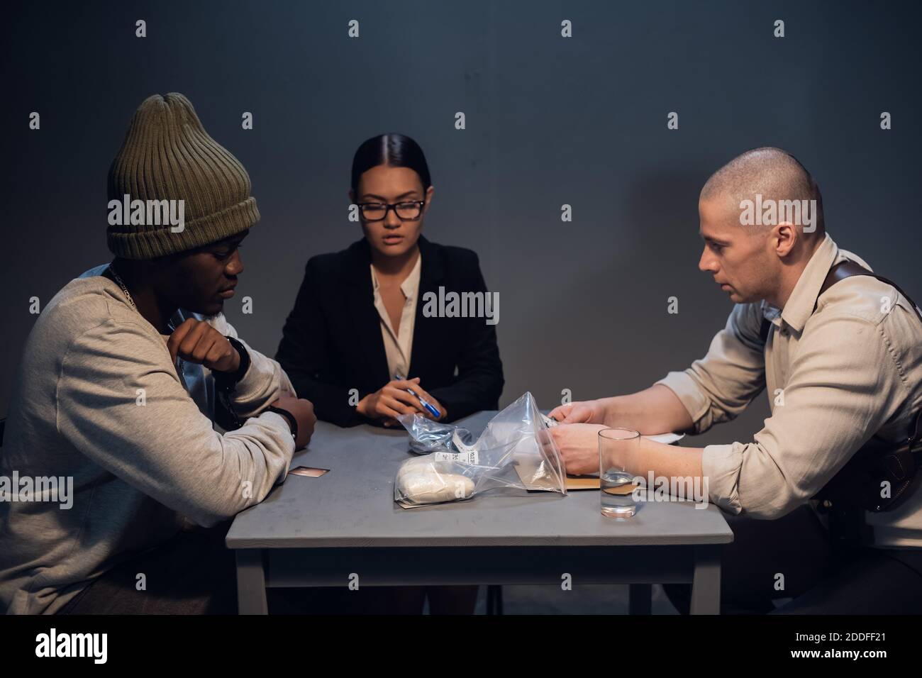 A black drug addict is interrogated at a police station by an ...