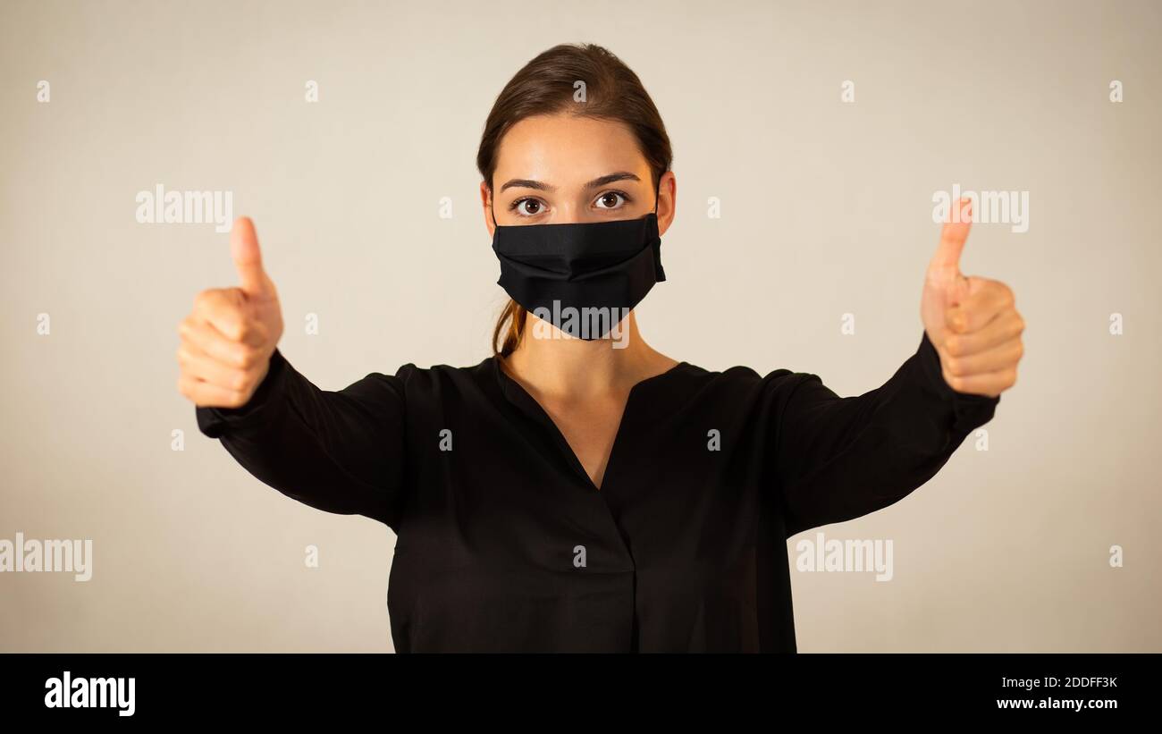 Positive woman wearing black face mask showing her thumbs up Stock ...