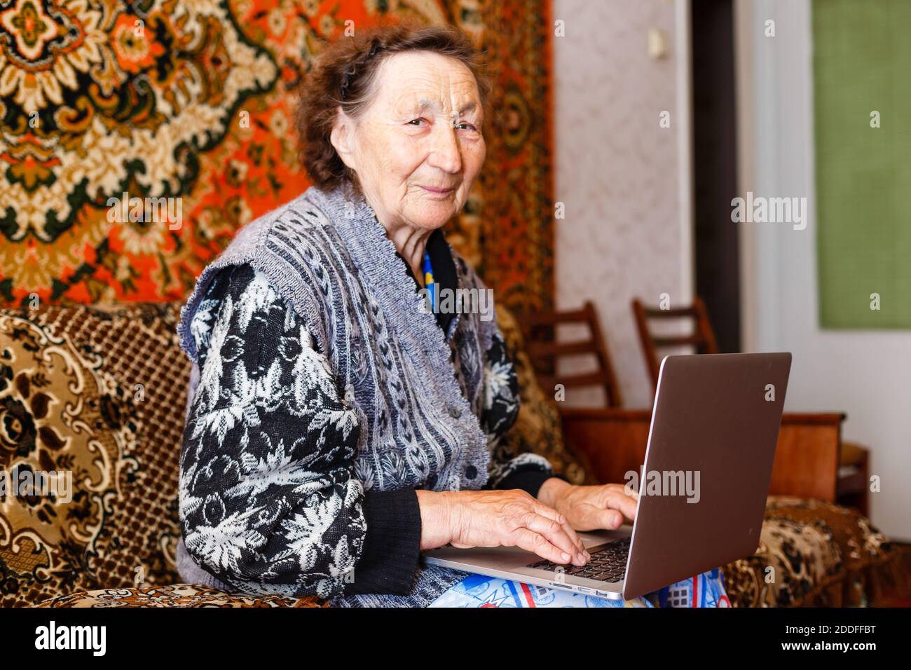 Old woman working on laptop computer at home, Grandma using notebook ...