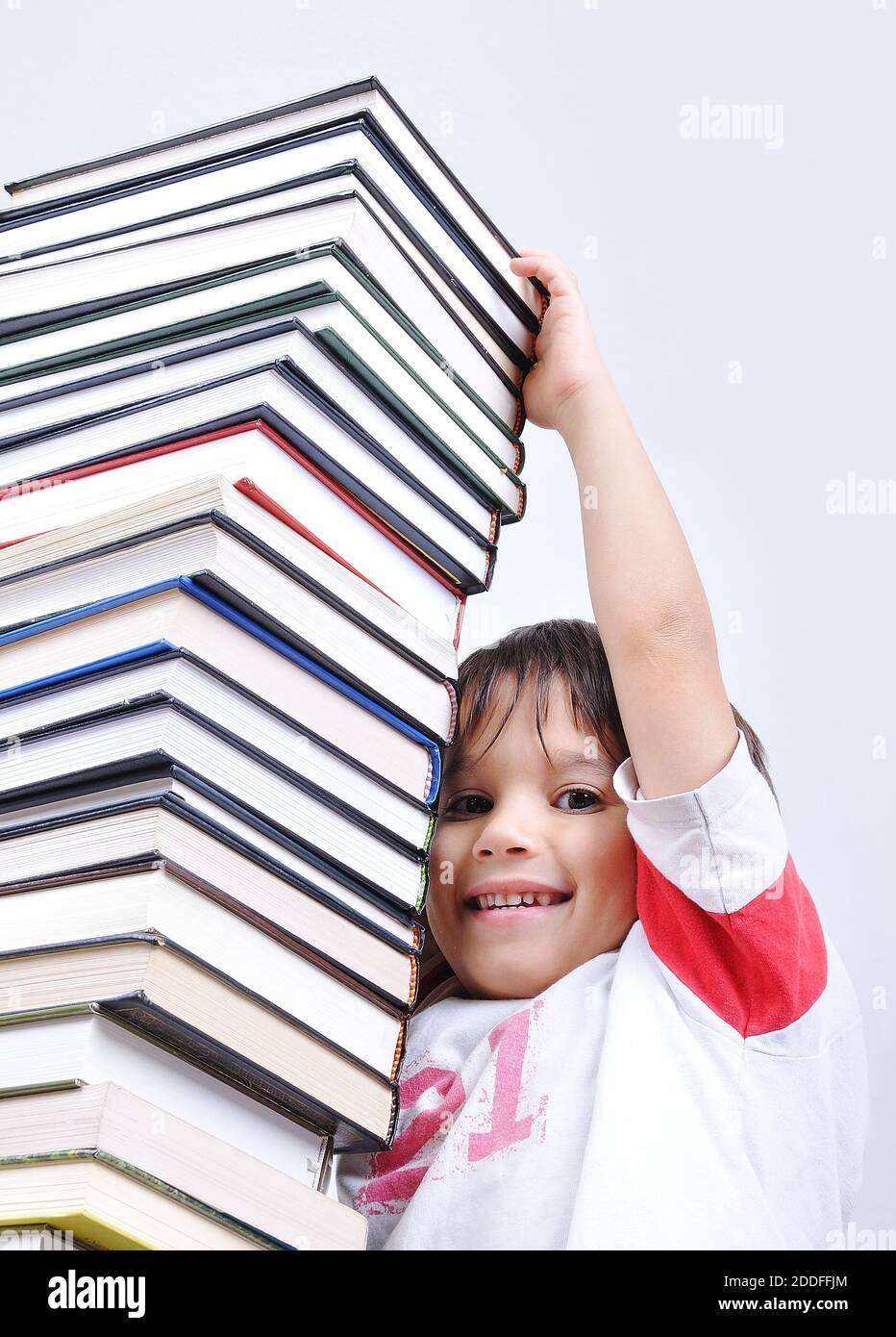 A big tower of many books vertical and kid Stock Photo - Alamy