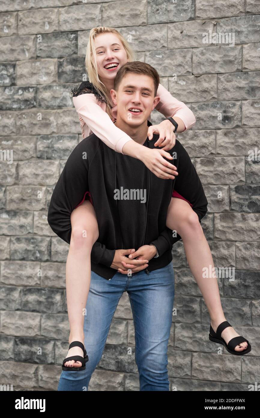 Happy man giving piggyback ride to his girlfriend and laughing near ...