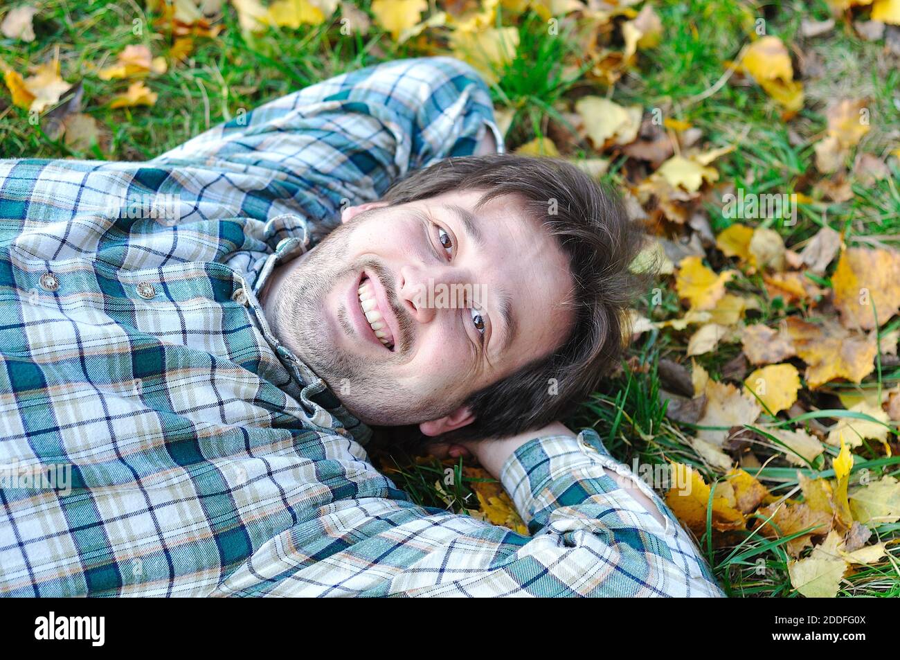 Happy positive young man on fall ground Stock Photo - Alamy