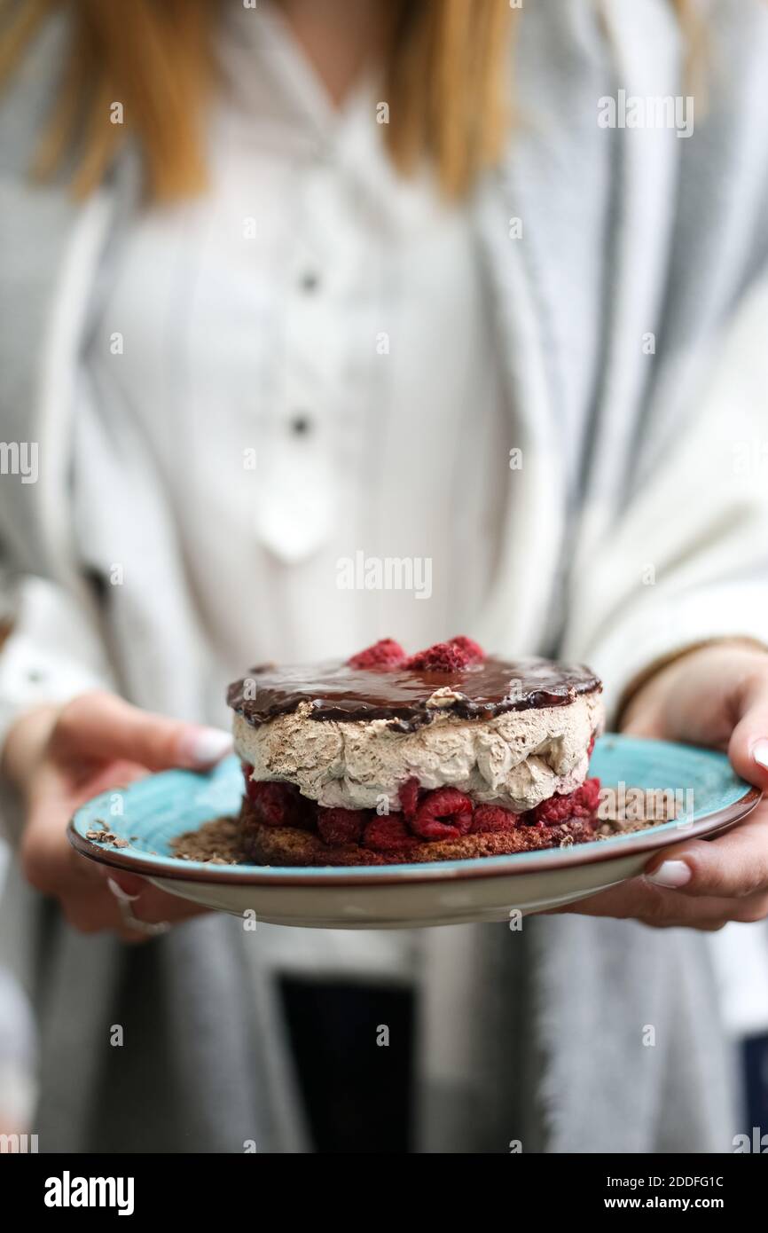 A vertical shot of a lady serving delicious dessert with raspberries ...