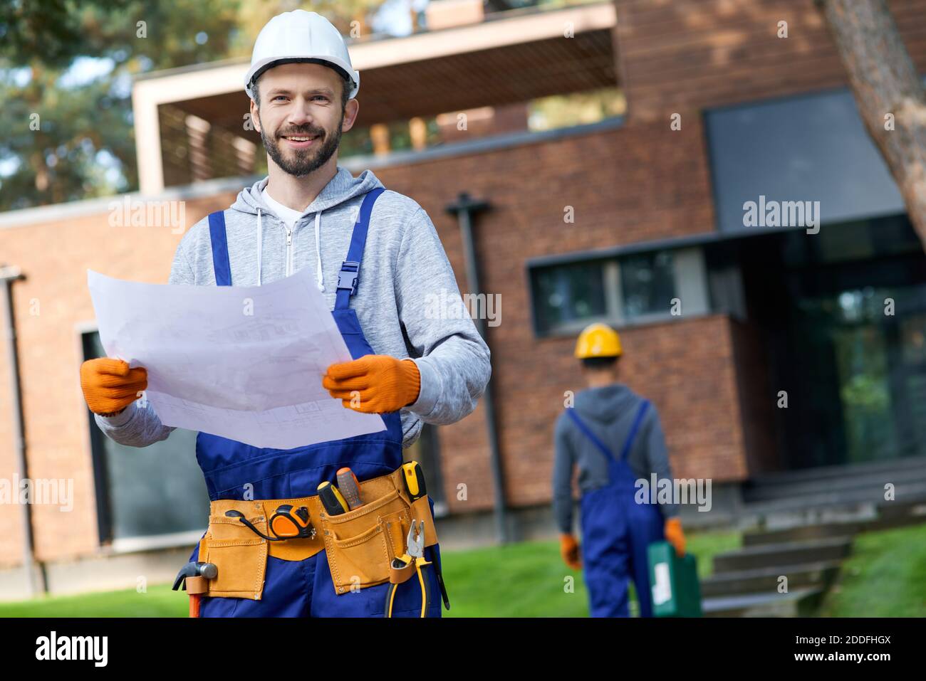Portrait of positive builder looking at camera while standing outdoors ...