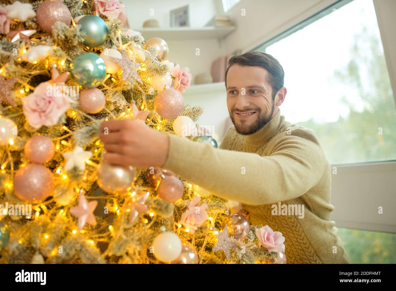 Bearded handsome man decorating new year tree Stock Photo - Alamy