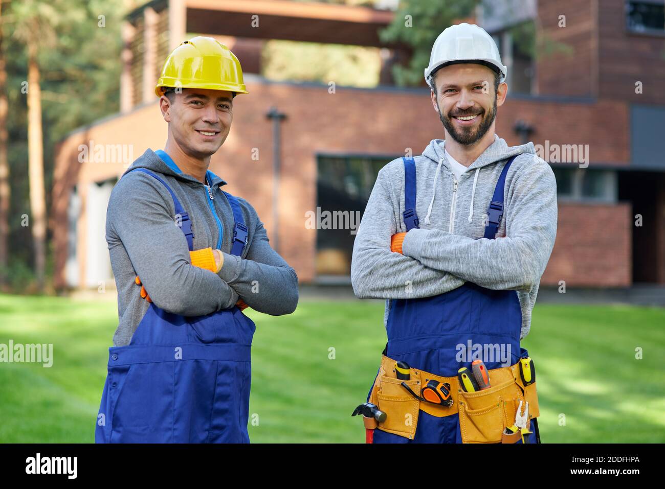 Portrait of two handsome young male engineers in hard hats smiling at ...