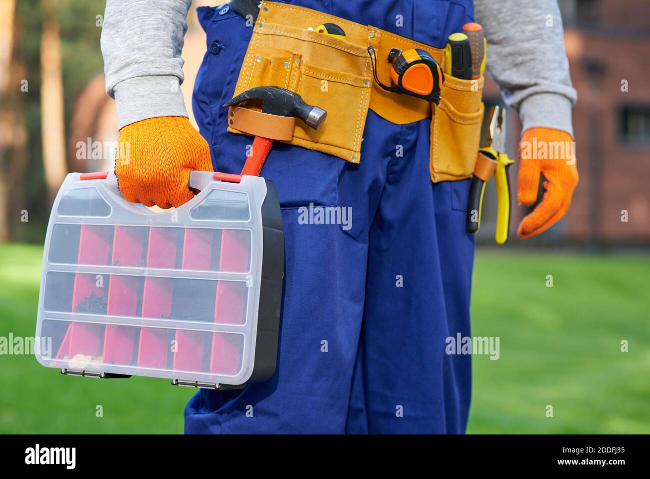 Male builder wearing tool belt carrying toolbox at construction site ...