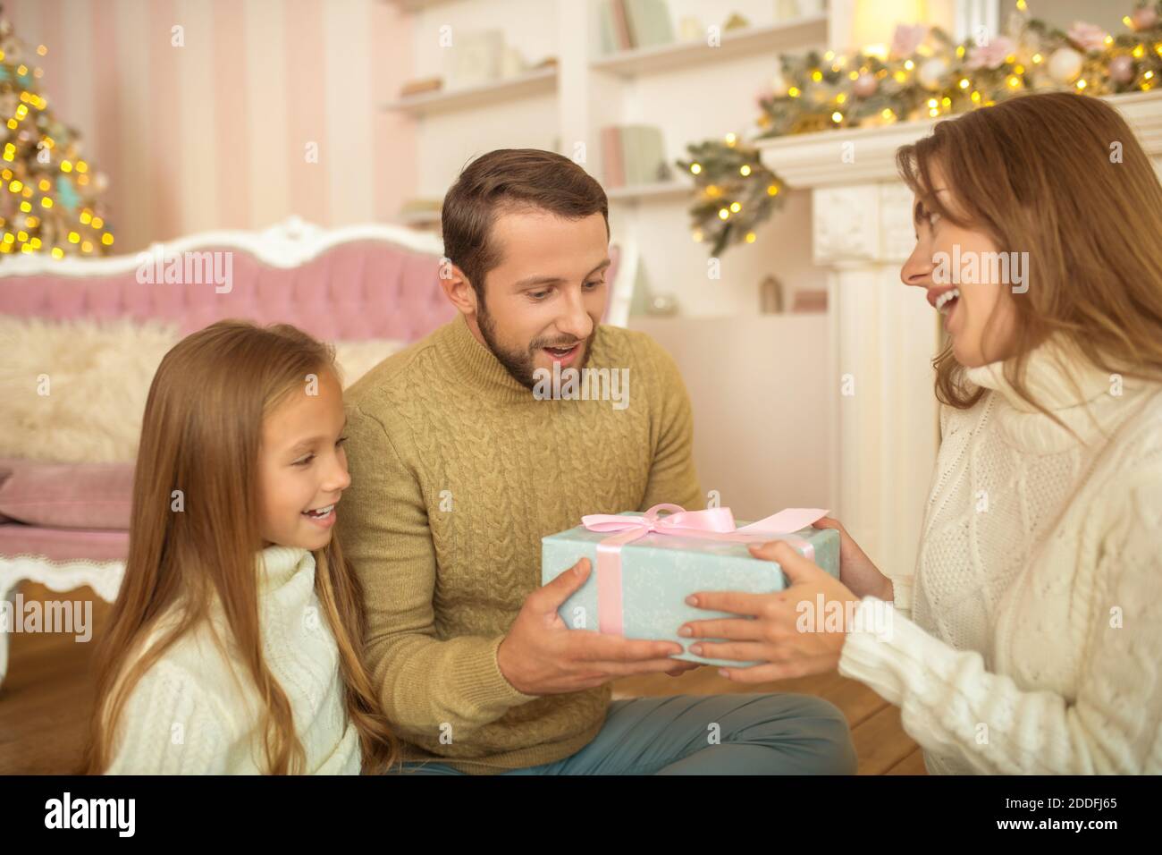Young family sitting on the floor and exchanging christmas gifts Stock ...