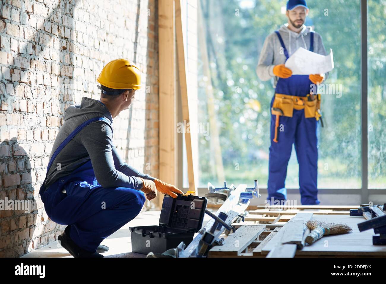 Young male engineer wearing overalls and hard hat working at cottage ...