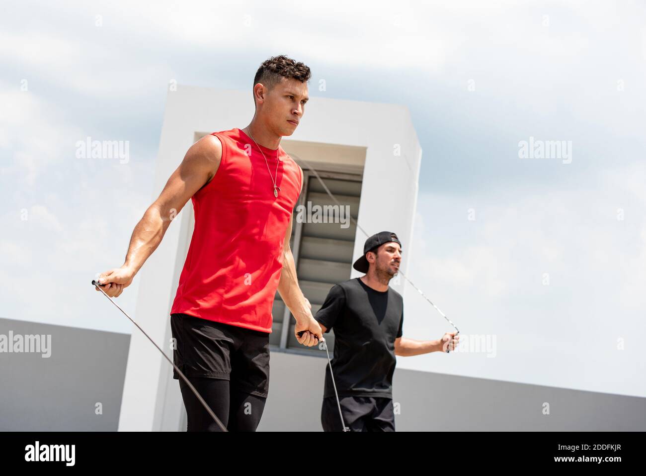 Two handsome Caucasian sportsmen doing morning outdoor jumping rope ...