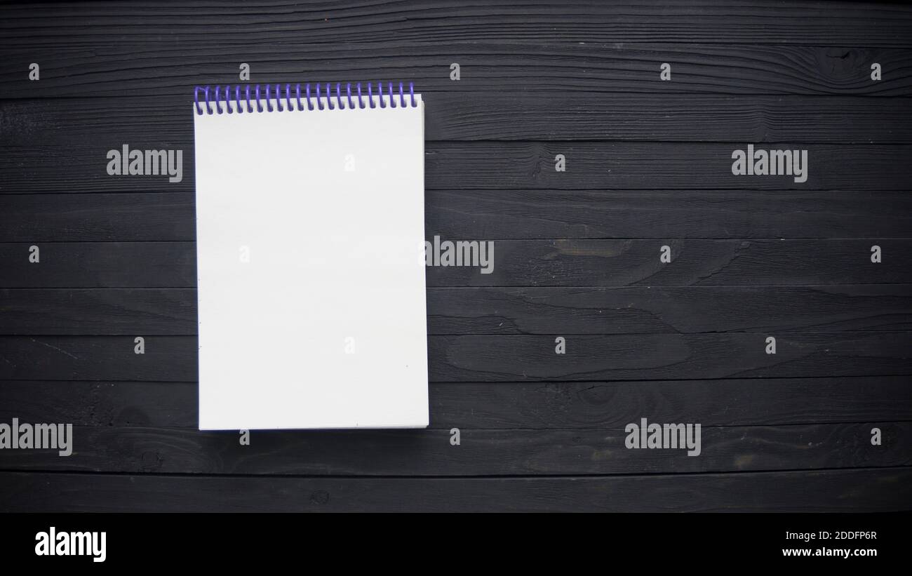 Blank paper notebook on brown wooden table background. Top view with ...