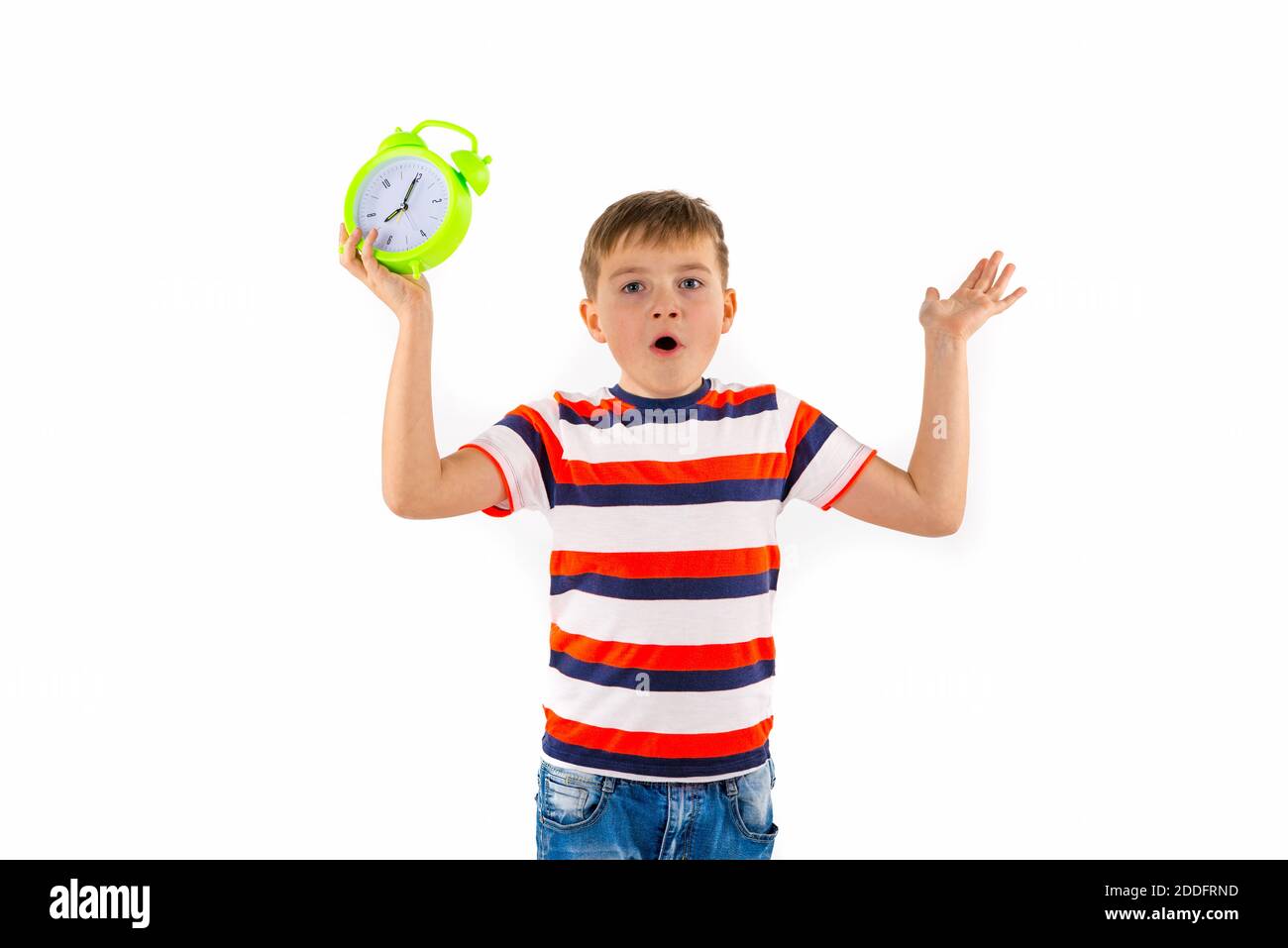 Upset cute boy holding alarm clock on white isolated studio background ...