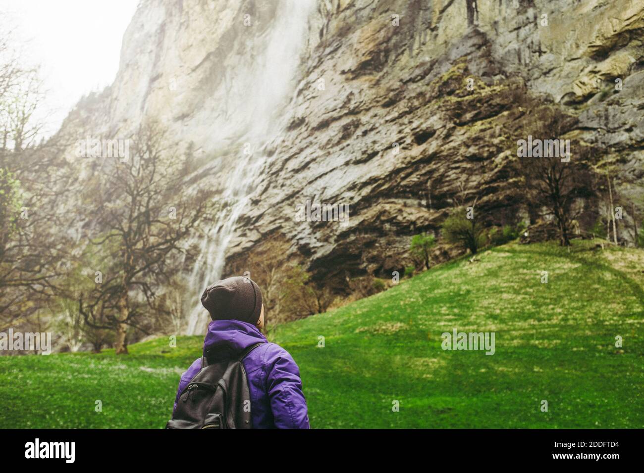 A woman traveler standing and watching a beautiful mountain waterfall ...
