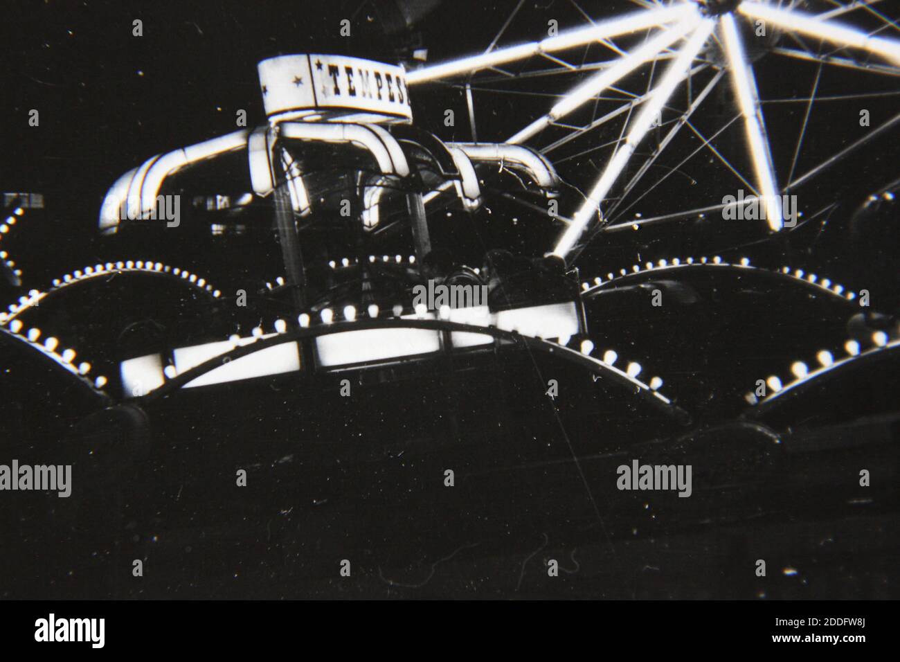 Fine 1970s vintage black and white photography of a carnival ride lit up at night with bright ...
